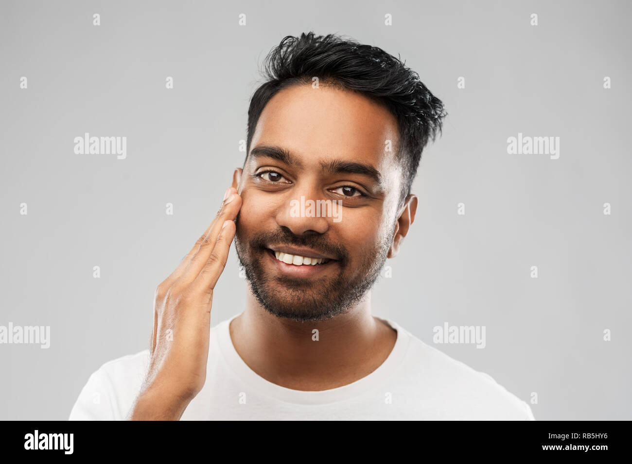 smiling indian man touching his face Stock Photo - Alamy