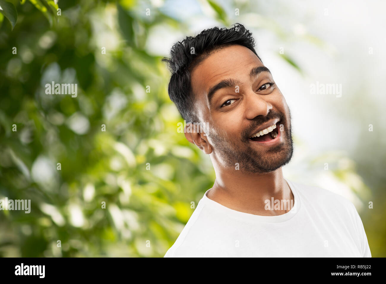 laughing indian man over green natural background Stock Photo - Alamy