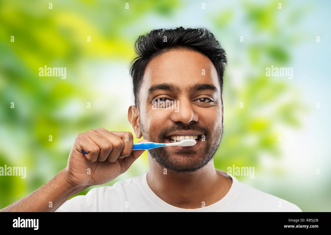 indian man cleaning teeth over natural background Stock Photo - Alamy