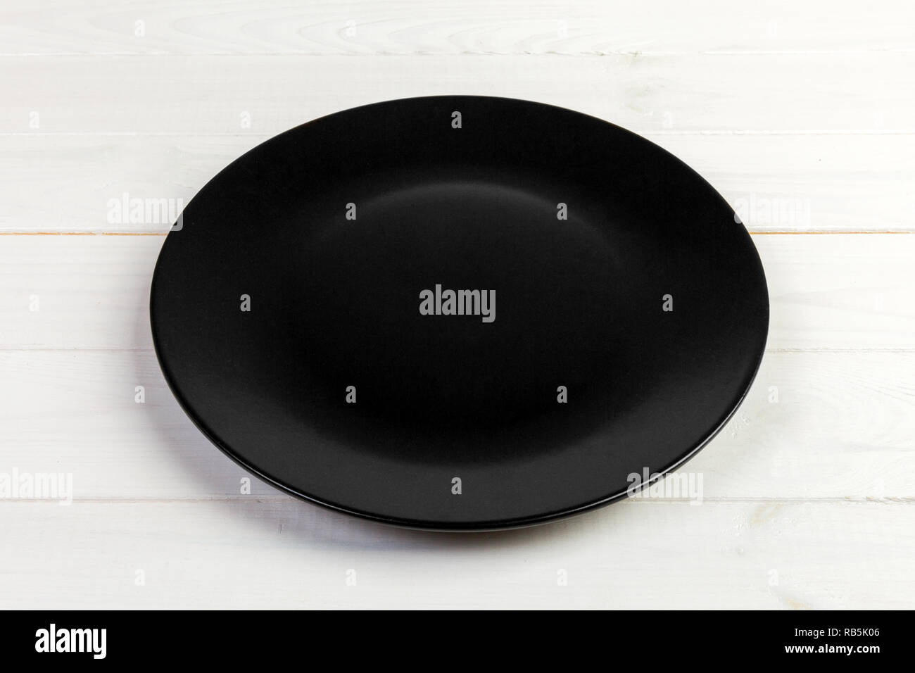 Perspective view. Empty black matte plate on white wooden background ...