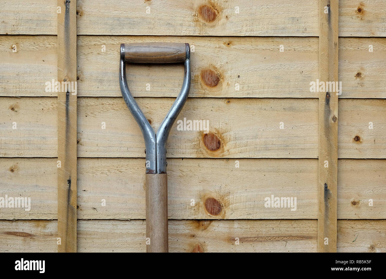 spade handle leaning against garden timber fence panel Stock Photo - Alamy