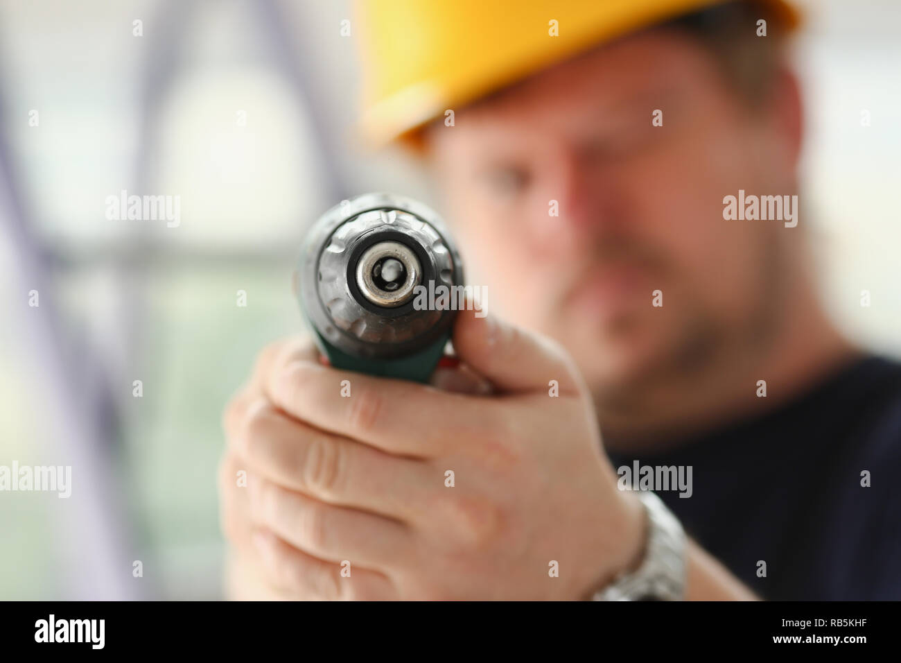 Arms of worker using electric drill closeup Stock Photo - Alamy