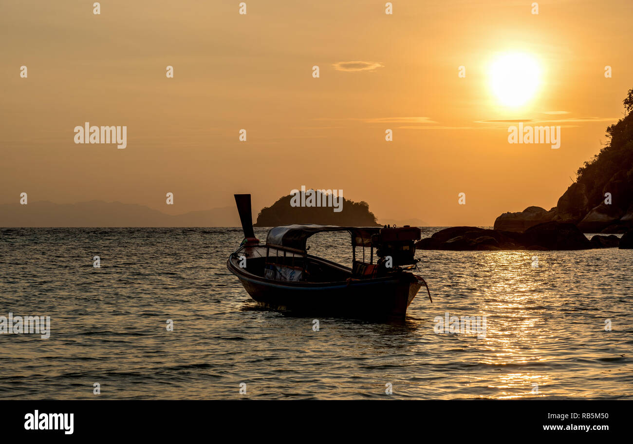 Early morning sunrise over the sea and a fishing boat Stock Photo - Alamy