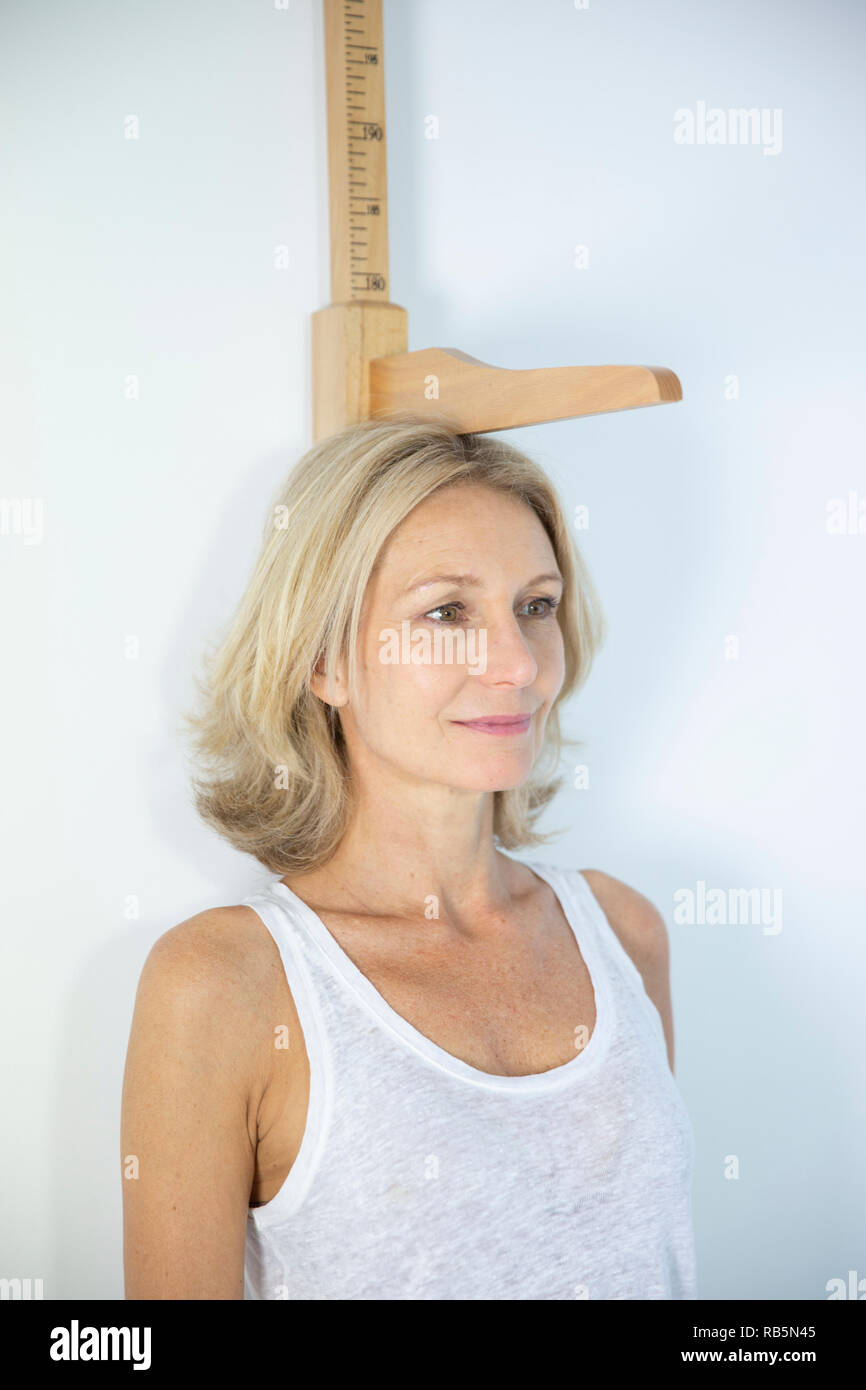 Woman measuring herself with a height measuring rod Stock Photo - Alamy