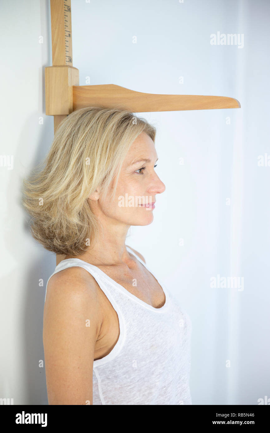 Woman measuring herself with a height measuring rod Stock Photo - Alamy