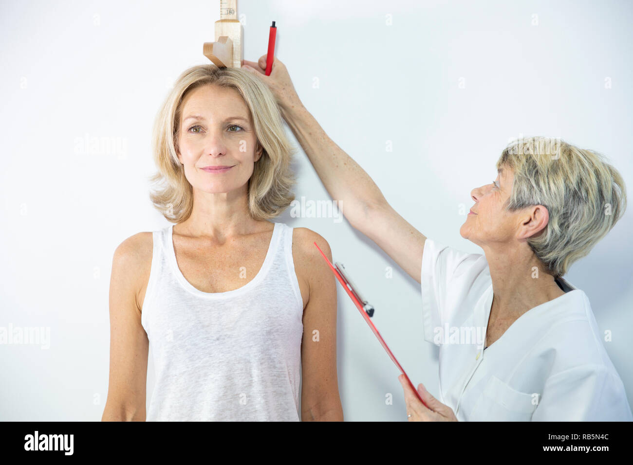 Woman measuring herself with a height measuring rod Stock Photo - Alamy