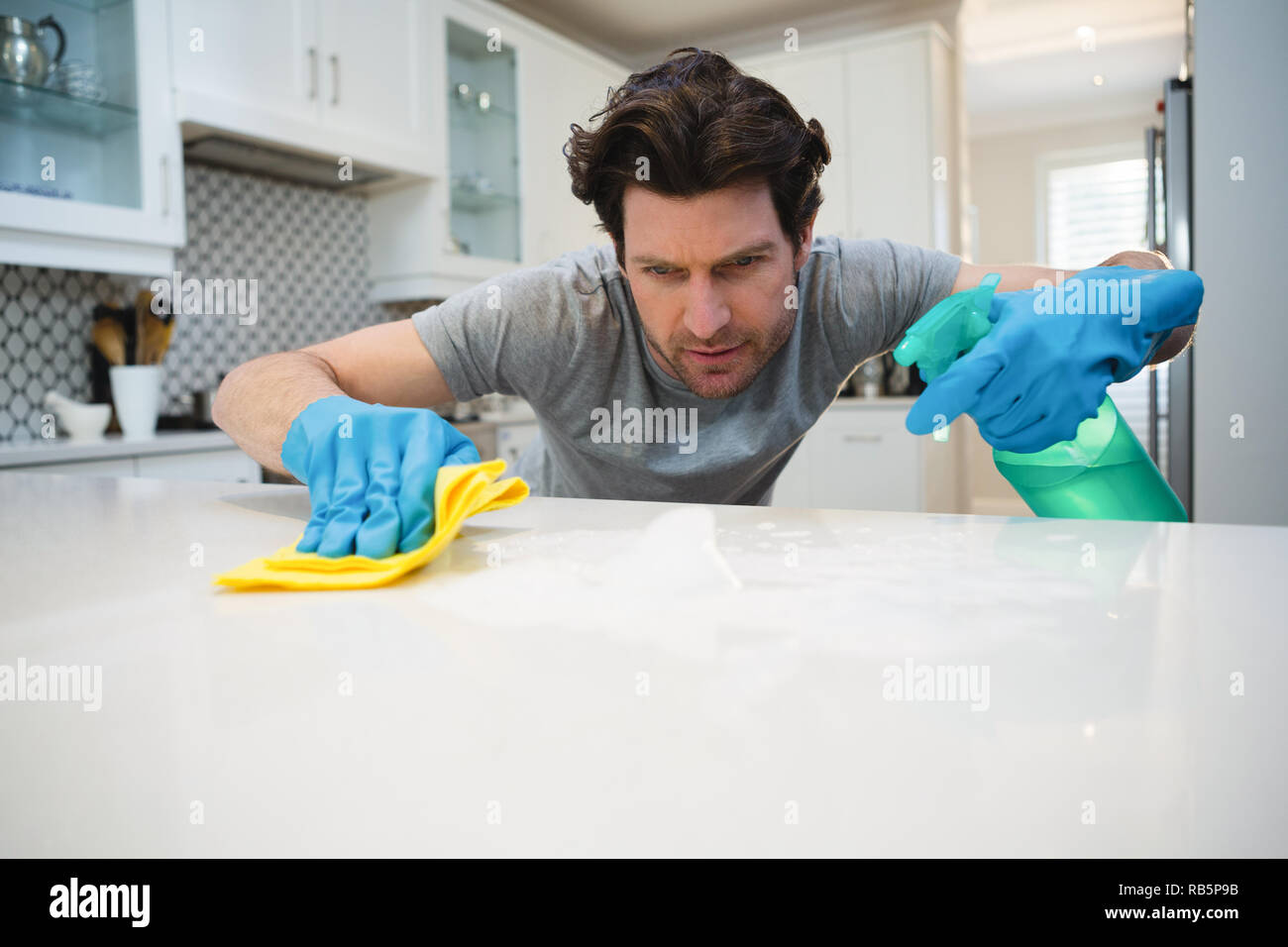 Man cleaning kitchen worktop at home Stock Photo - Alamy