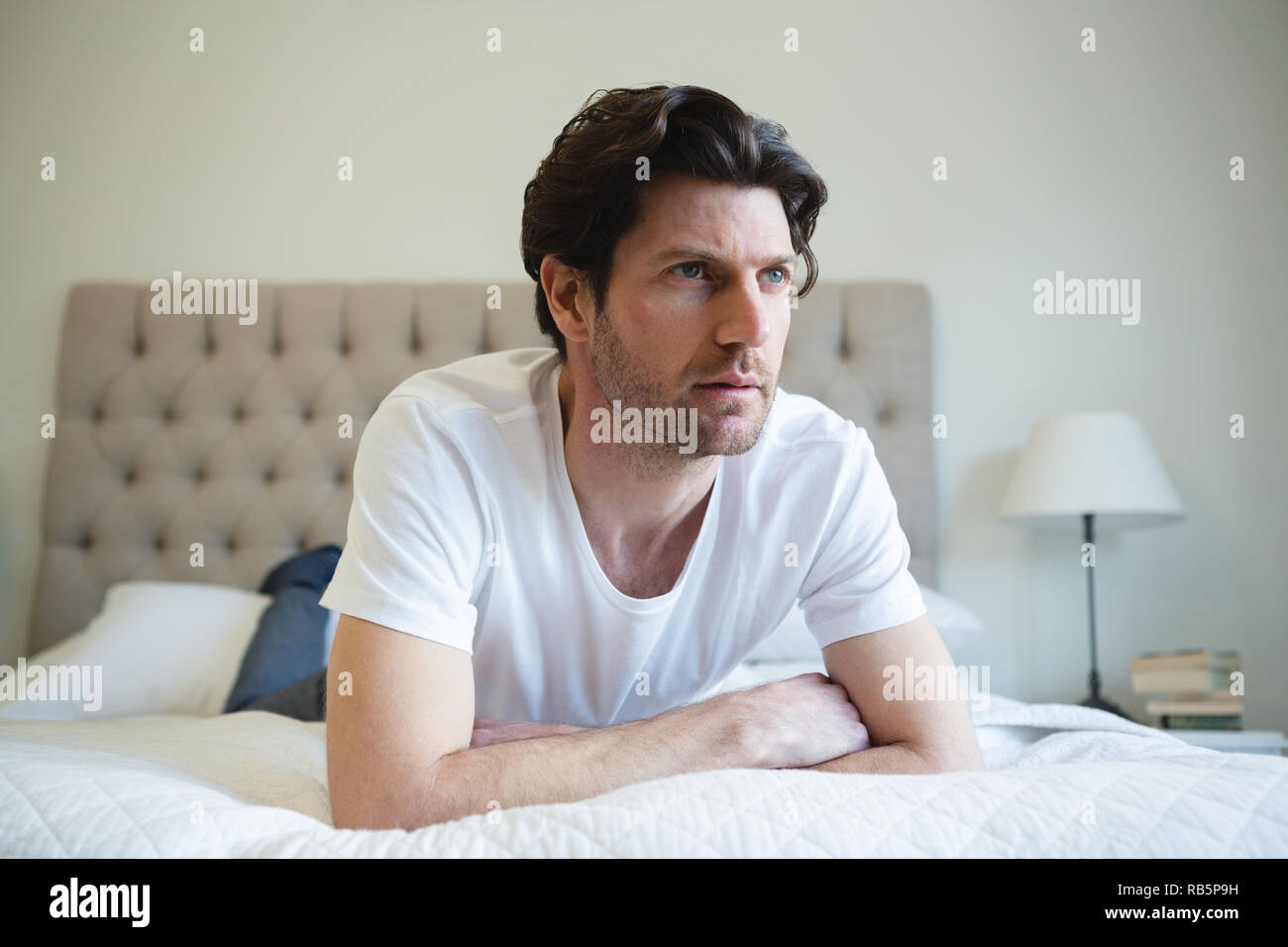 Man relaxing on bed in bedroom at home Stock Photo - Alamy