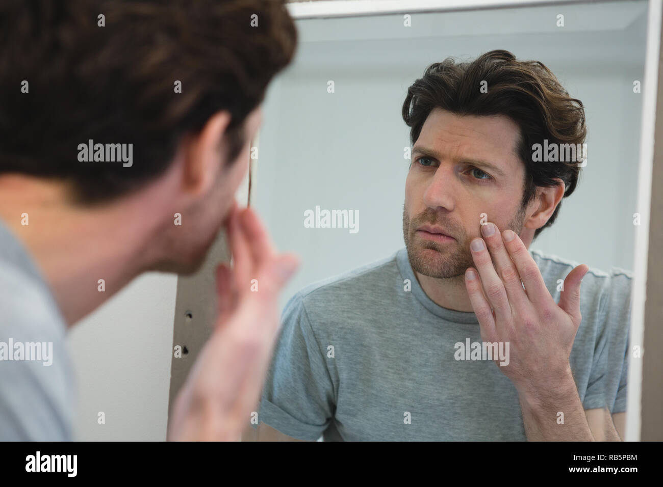 Man looking his face in mirror Stock Photo - Alamy