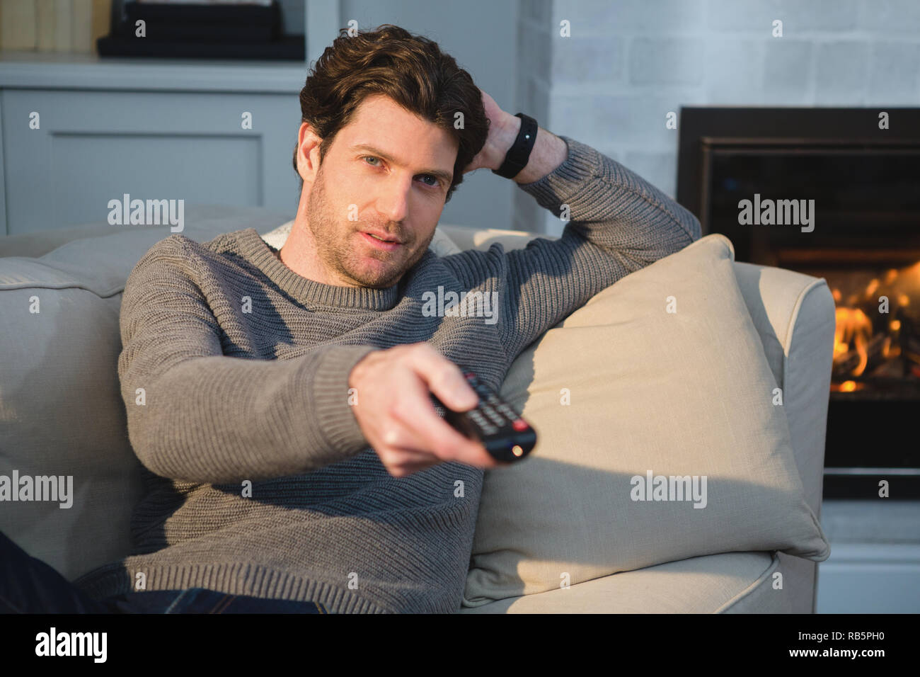 Man changing channel with remote control Stock Photo - Alamy