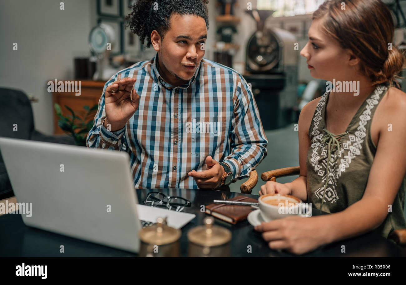 Entrepreneurs talking and being expressive in a coffee cafe with laptop ...