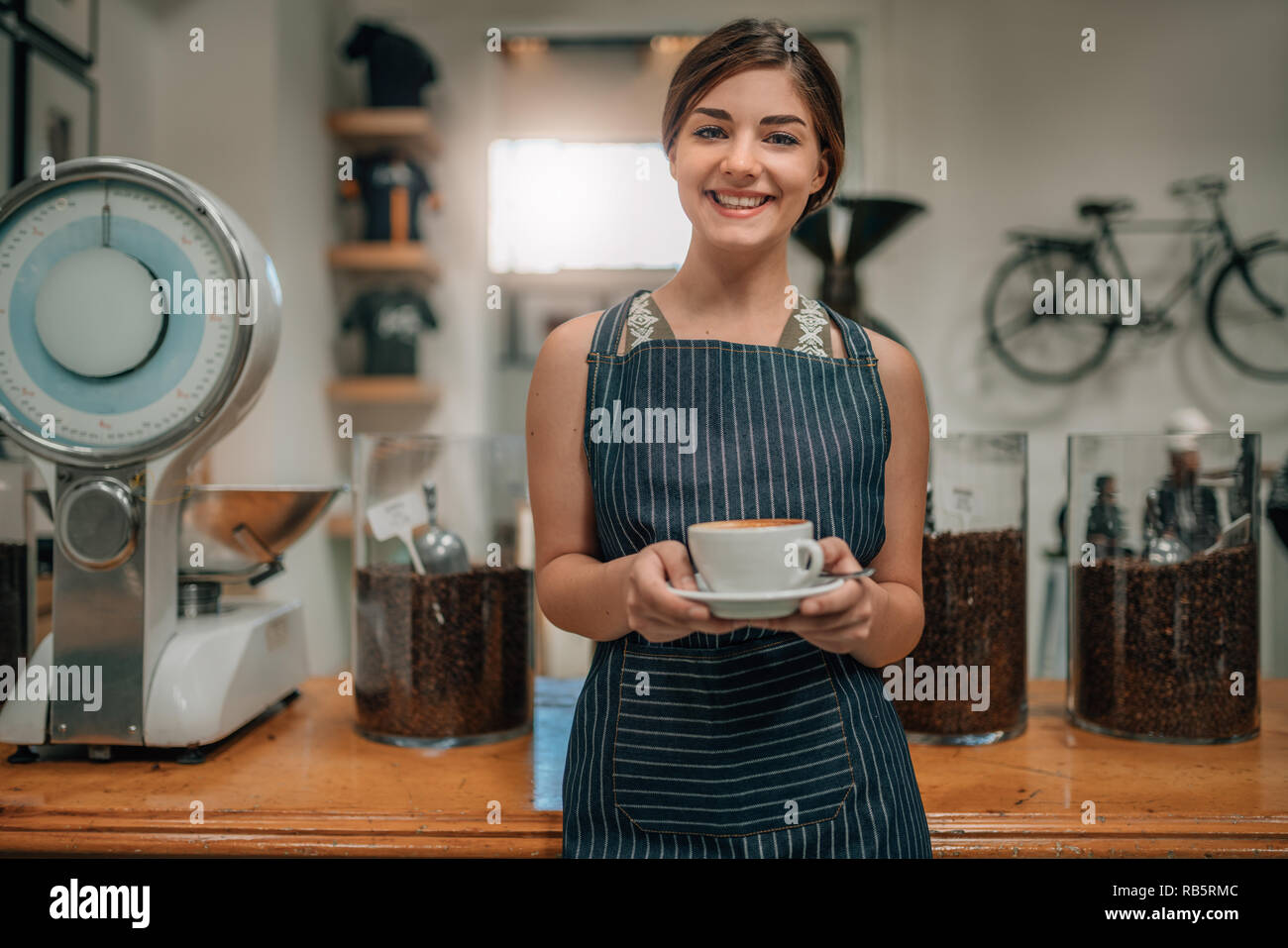 Young beautiful waitress smiling serving coffee with latte art while ...