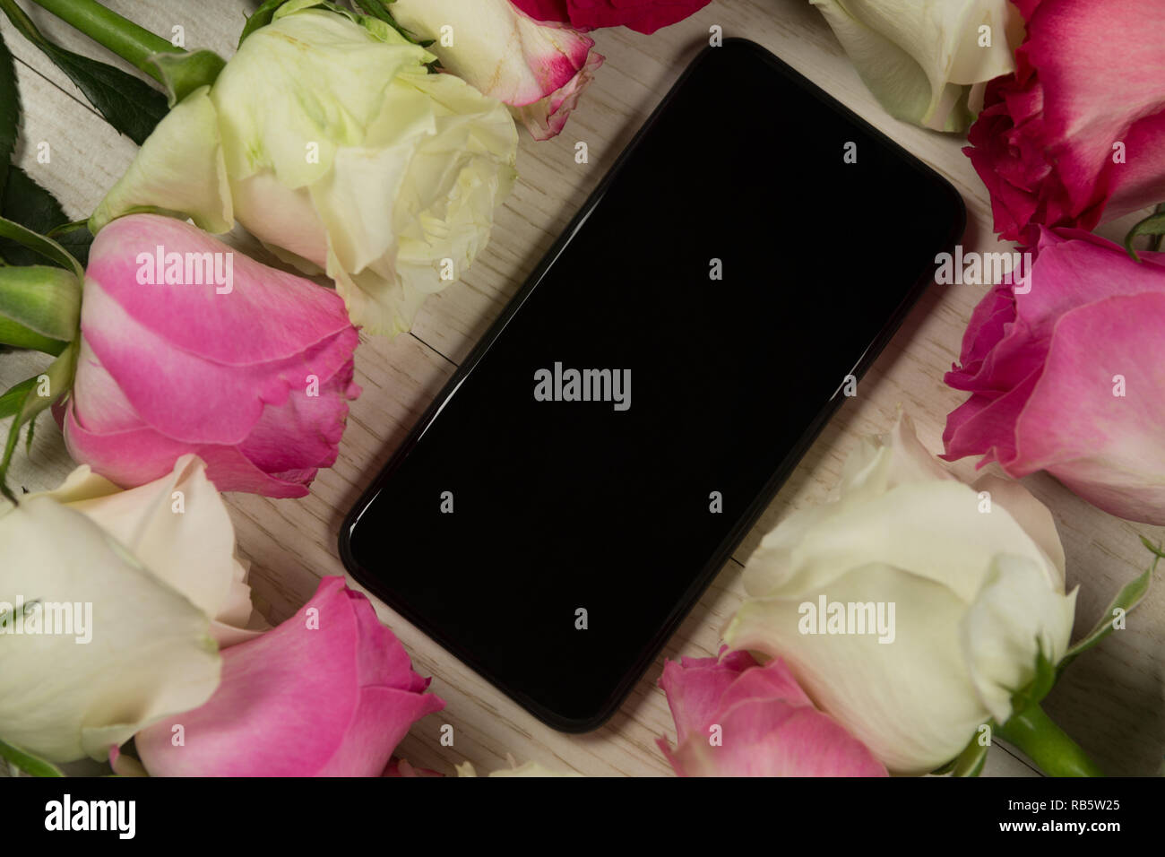 Mobile phone surrounded with rose flower Stock Photo - Alamy