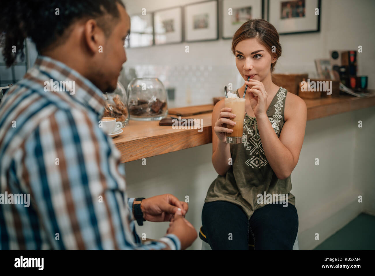 Beautiful generation z girl sipping on an iced coffee at bar counter of ...