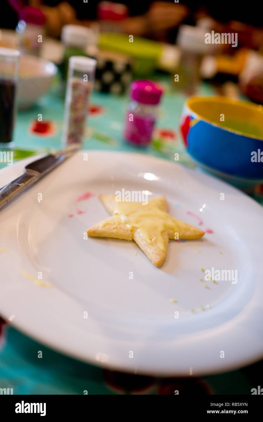 half decorated homemade cookie shaped like a star covered with cream ...