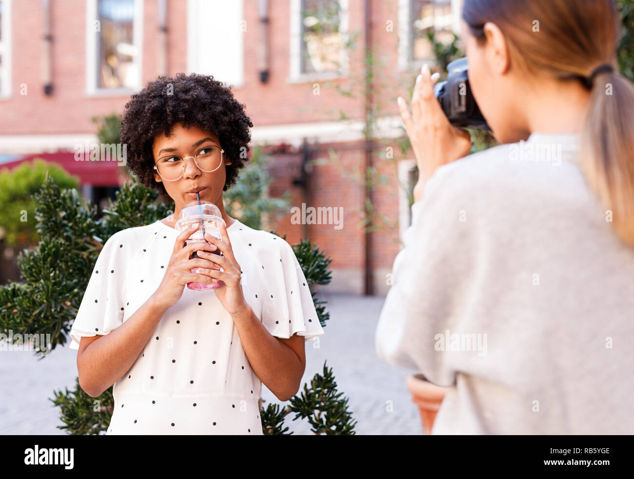 Woman photographer shooting a client. Girl drinking a juice while photo ...