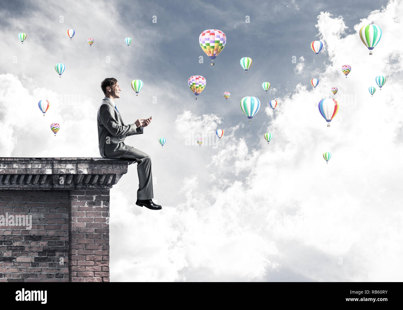Man on roof edge usinng smartphone and aerostats flying in air Stock ...
