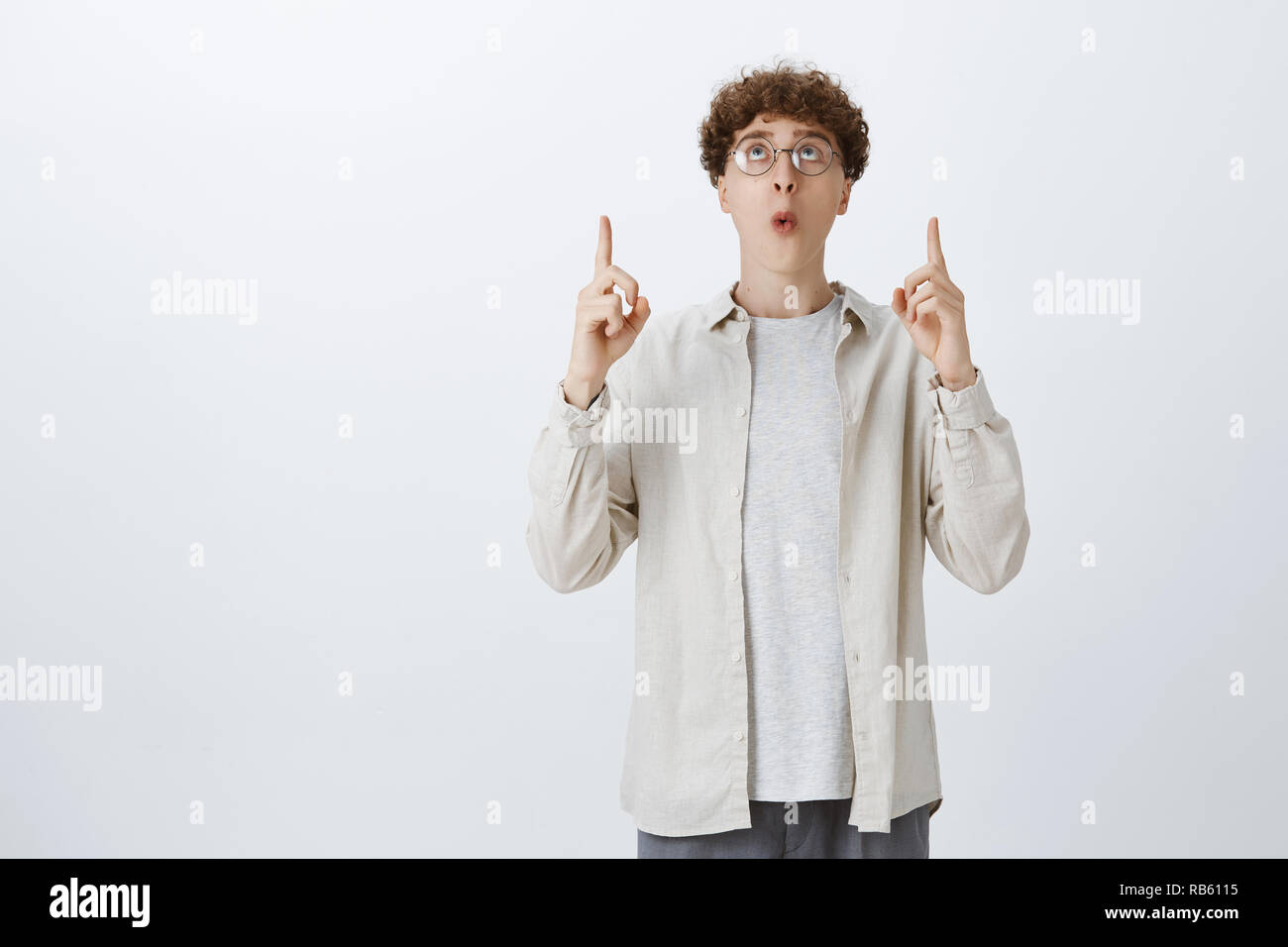 Impressed male programmer in shirt and round glasses with curly hair ...