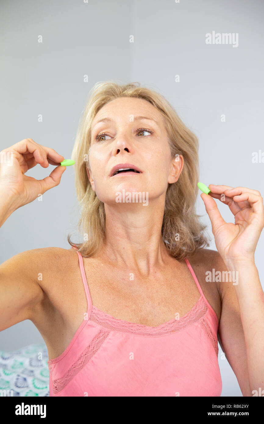 Woman using earplugs Stock Photo - Alamy
