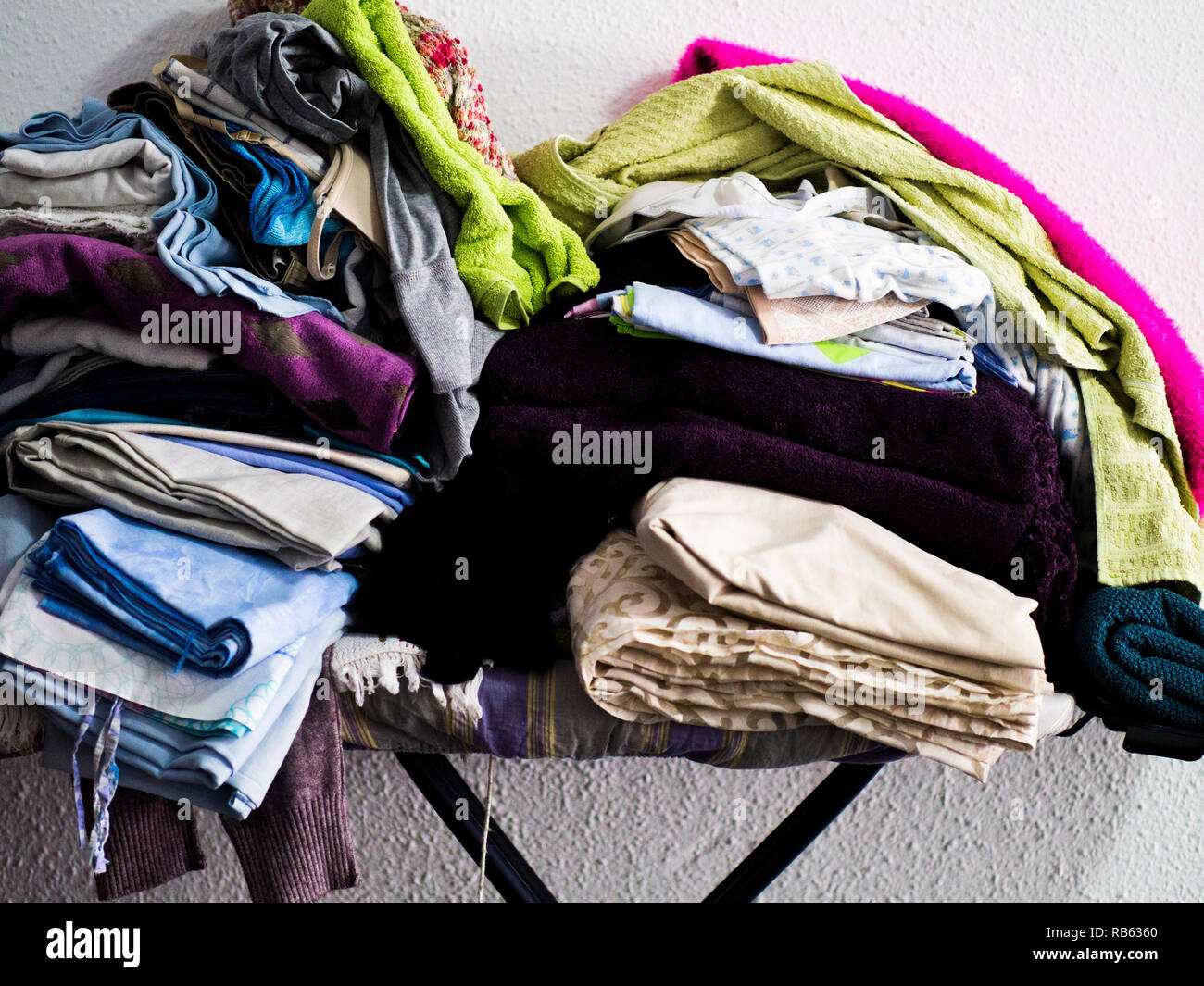 Pile of laundry on ironing board Stock Photo - Alamy