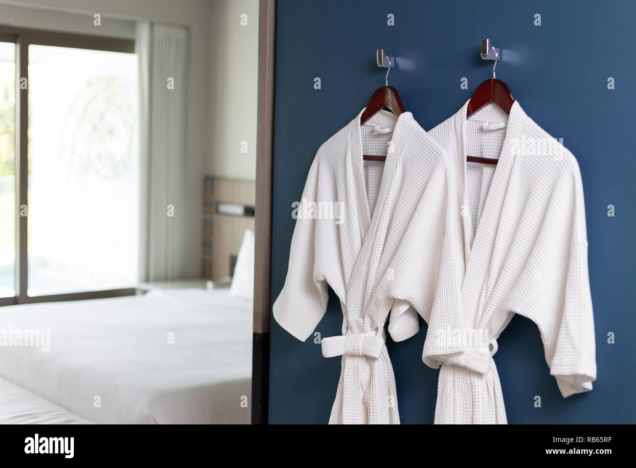 Clean white bathrobes hanging on wall Stock Photo - Alamy