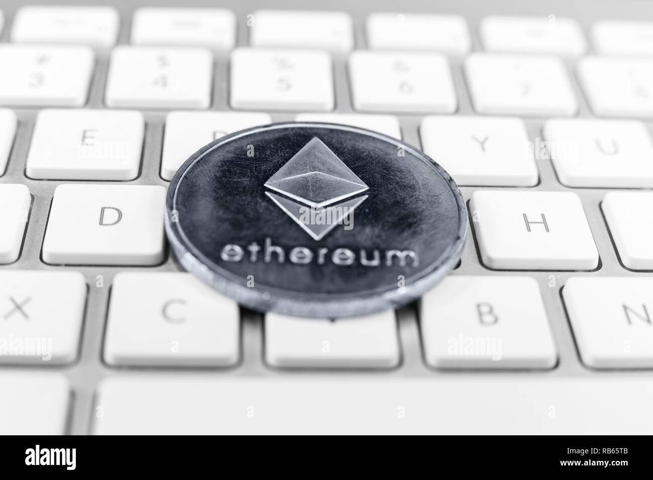 Ethereum coin lying on white computer keyboard Stock Photo - Alamy