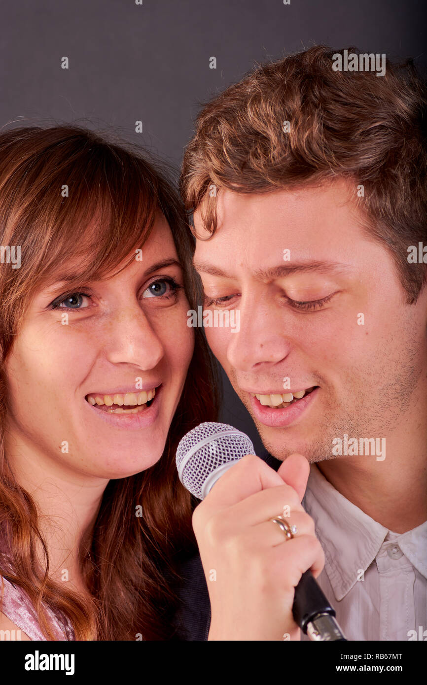 a guy and a girl stand and sing against Stock Photo - Alamy