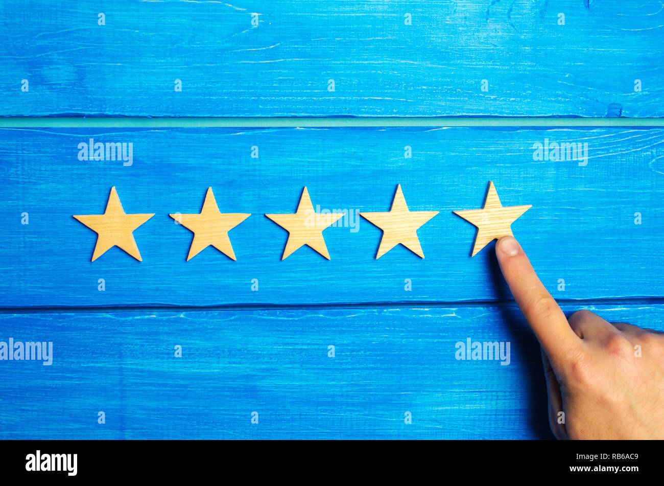 A woman's hand puts the fifth star. Quality status is five stars. A new ...