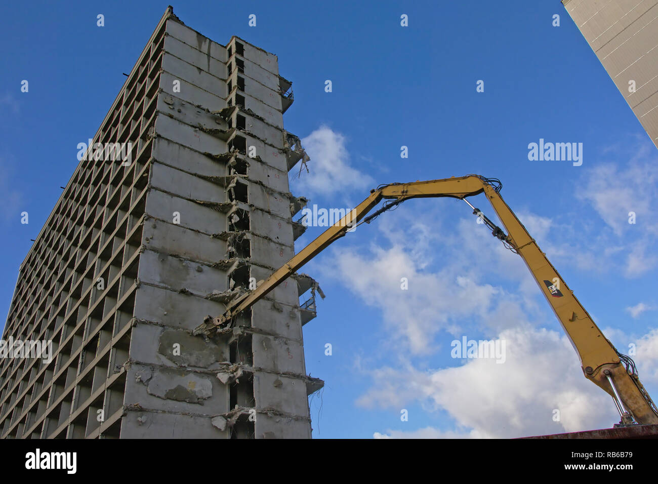 Yellow construction crane arm demolishing a stripped down concrete ...