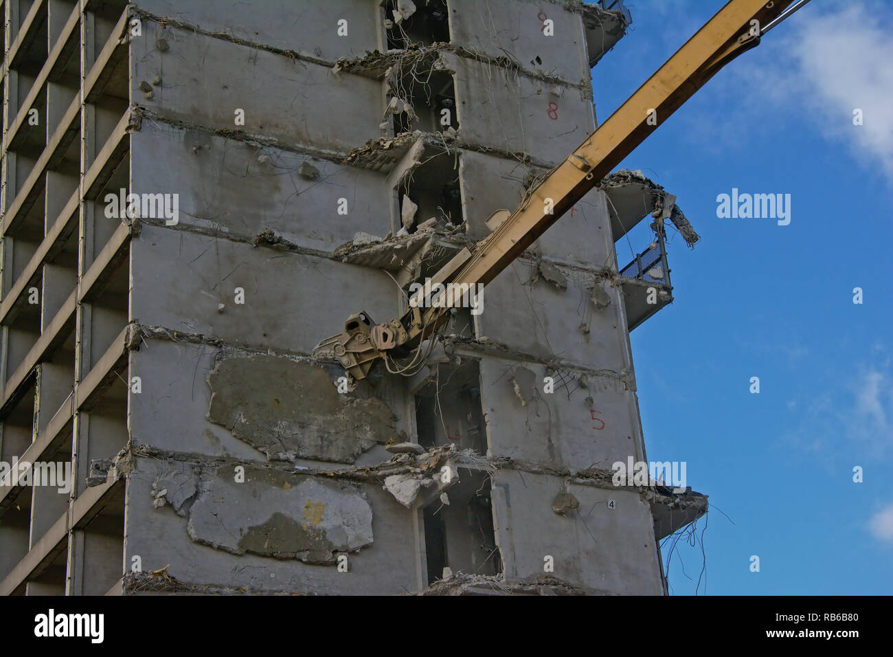 Yellow construction crane arm demolishing a stripped down concrete ...