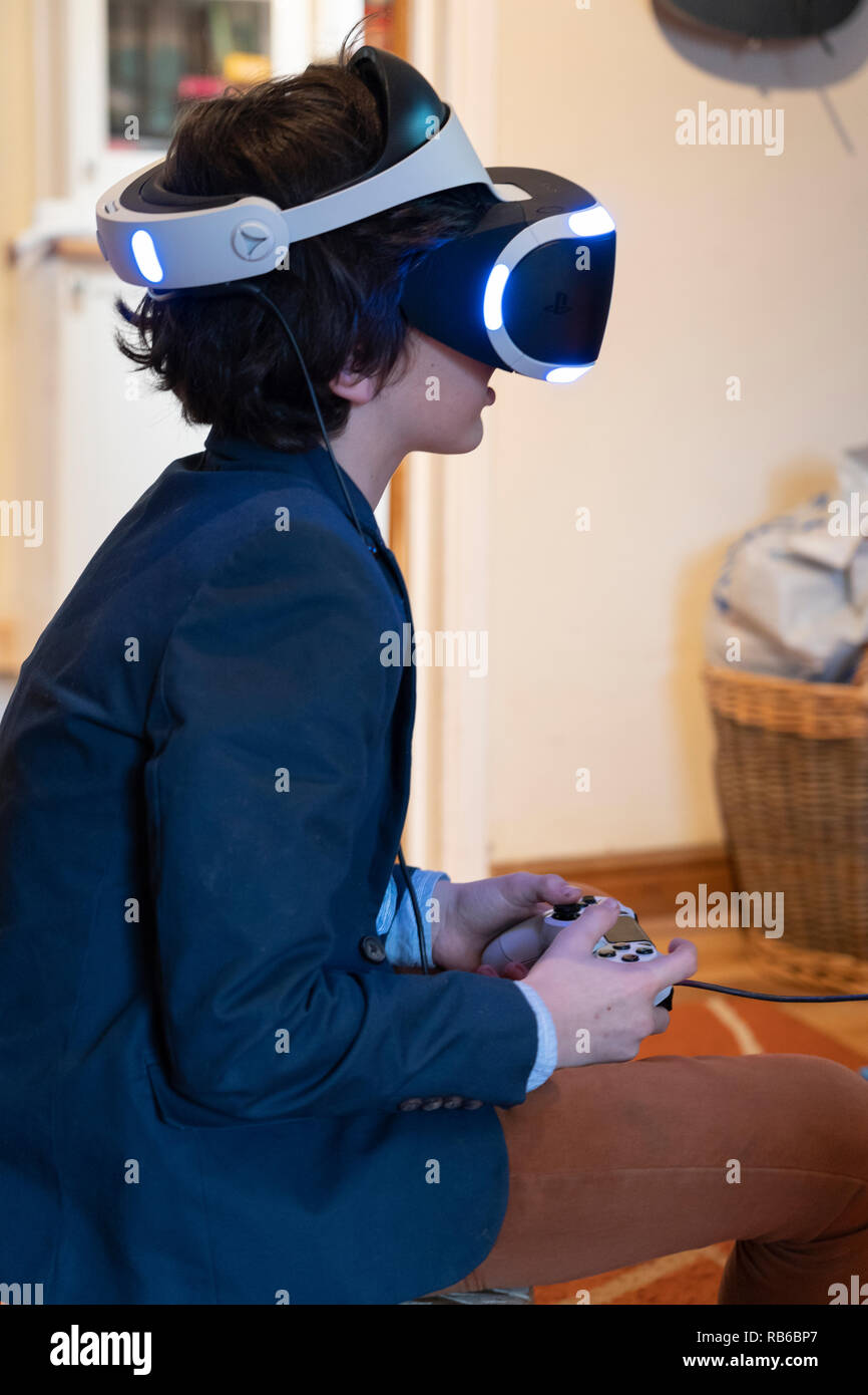 An 8 year old boy wearing a Sony Virtual Reality headset and playing a ...