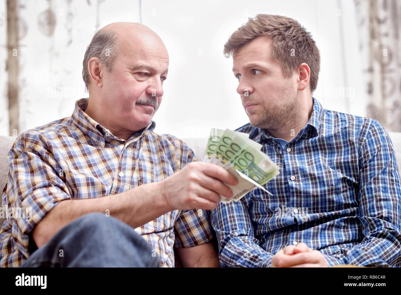 Elderly father lends money to his adult son. He helps his child deal ...