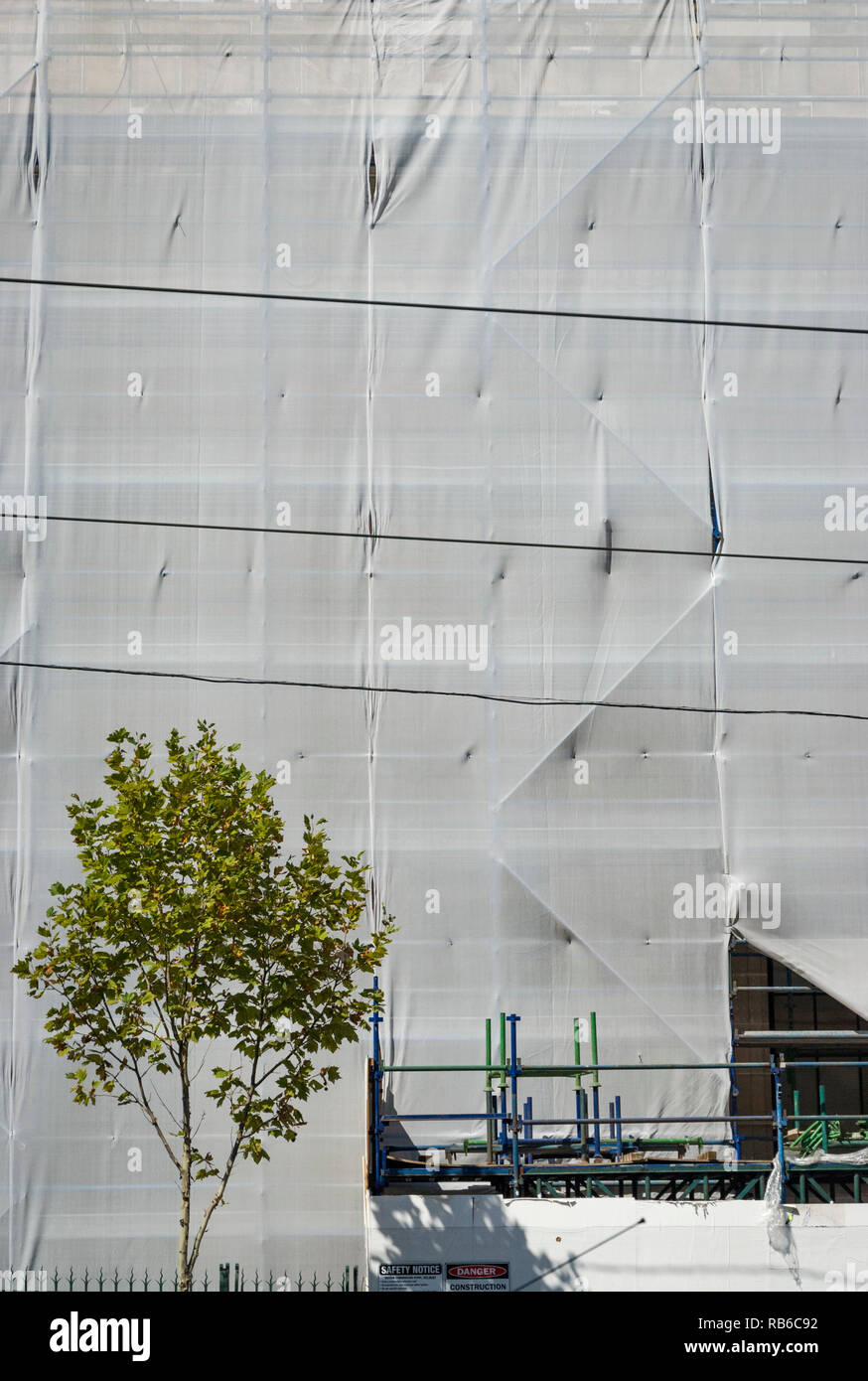 White wrapped scaffolding for work safety on a construction site with a ...