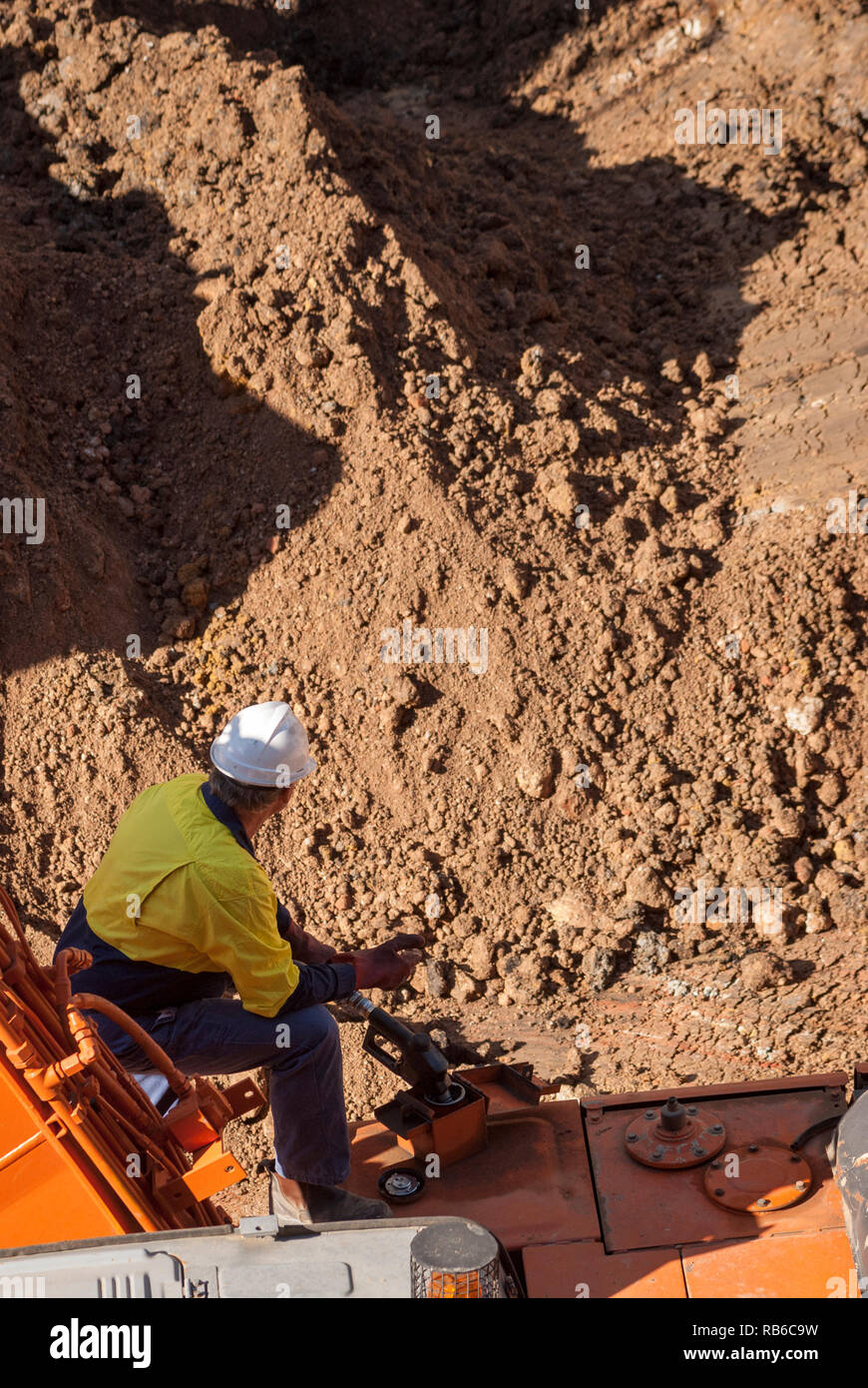 Workman on site, resting on his equipment in the shade Stock Photo - Alamy