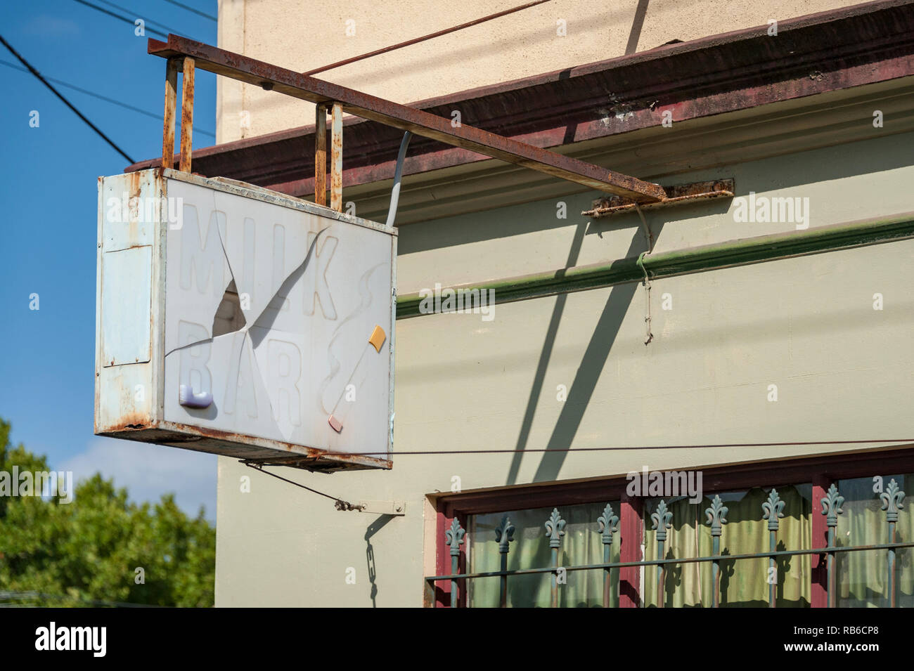 An old, faded and broken Milk Bar sign with cigarette attached to an ...