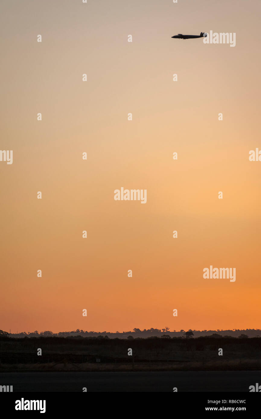 Vintage propeller driven airliner in silhouette against an orange ...