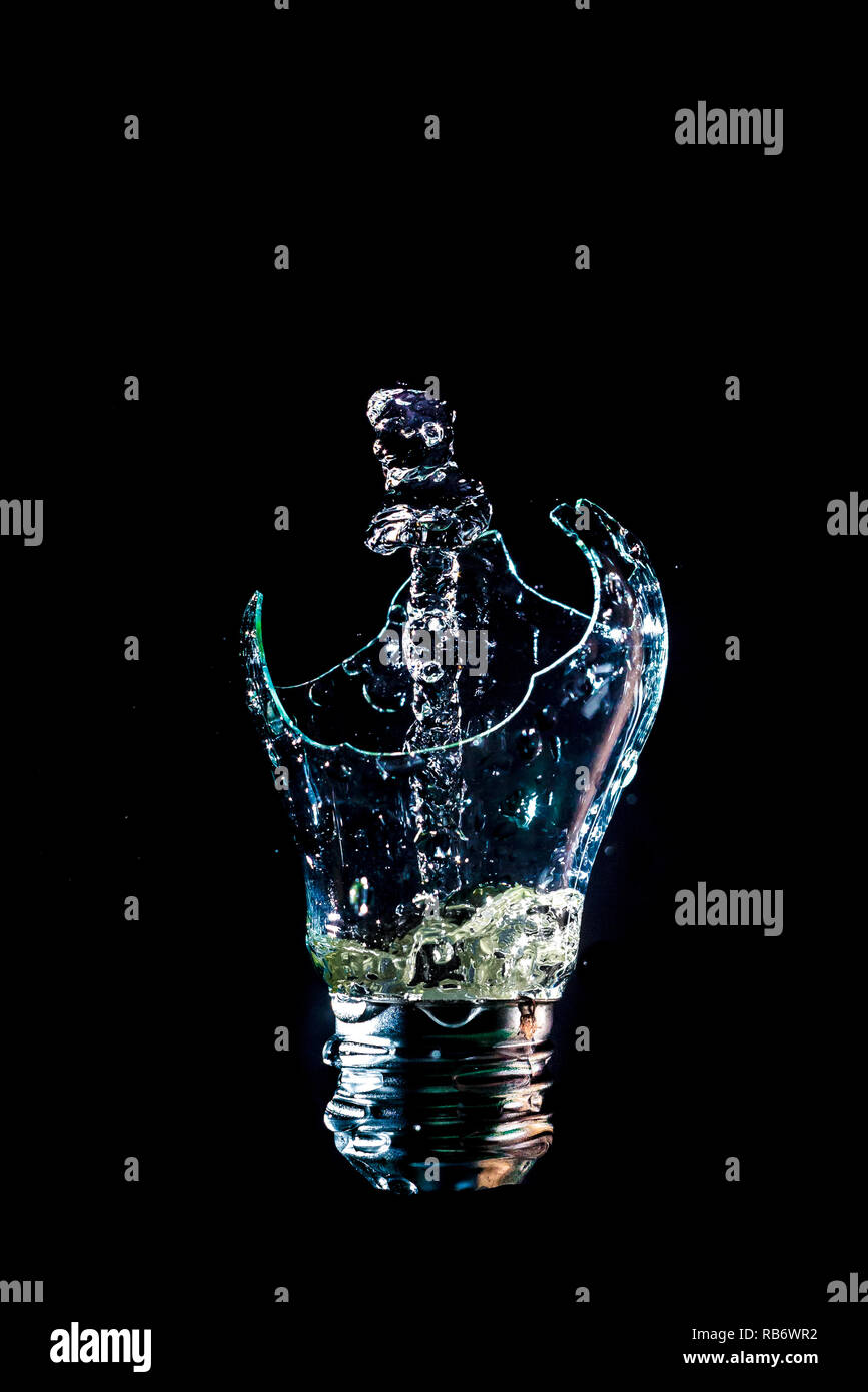 Creative broken light bulb with water fountain on isolated black ...