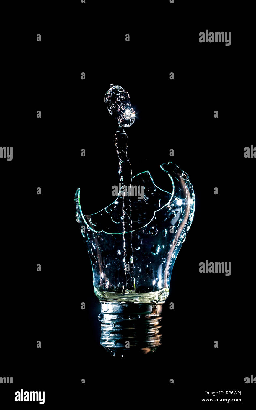 Creative broken light bulb with water fountain on isolated black ...