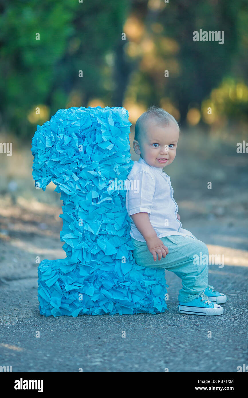 little baby boy sitting close to number one birthday number blue color ...