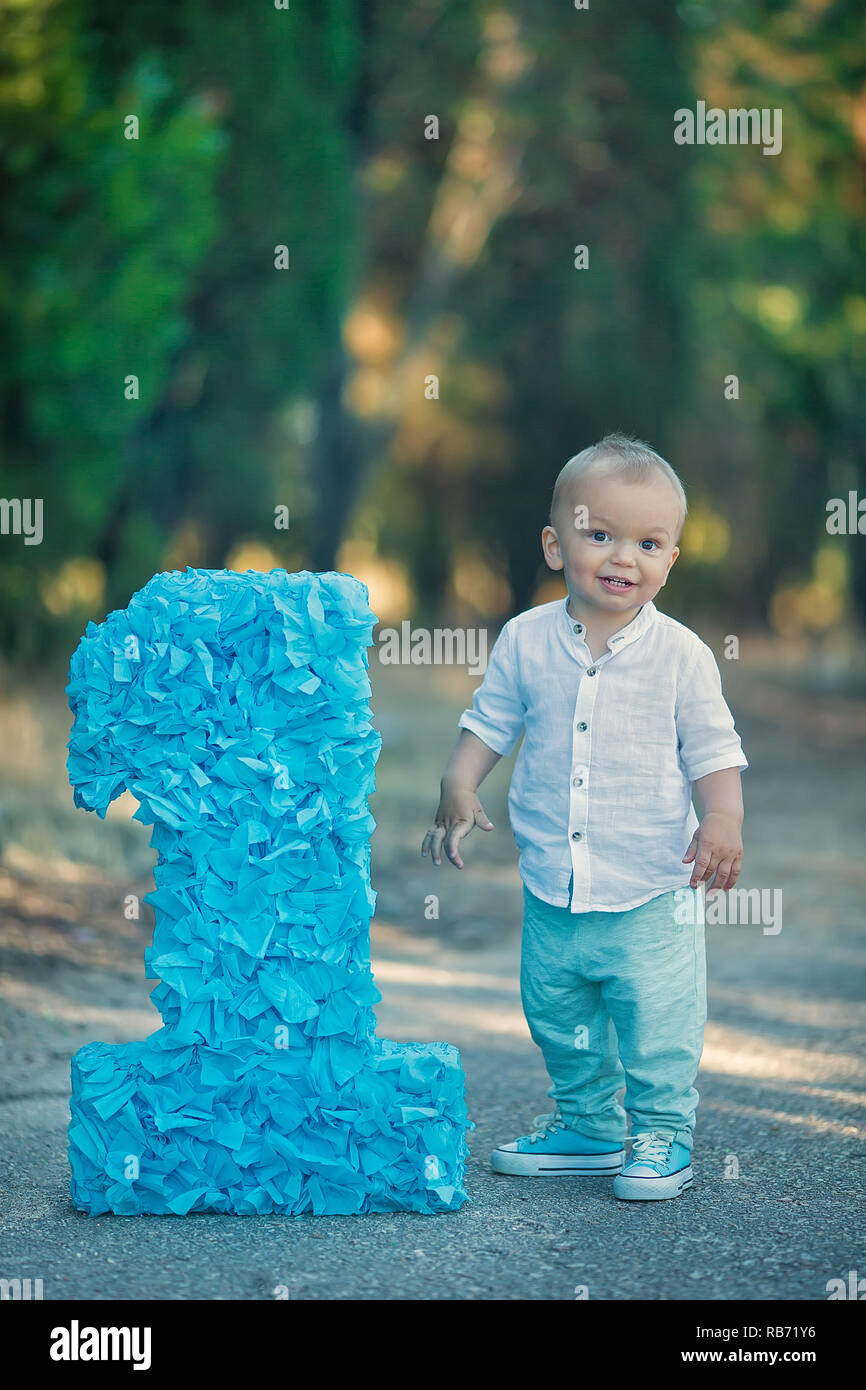 little baby boy sitting close to number one birthday number blue color ...