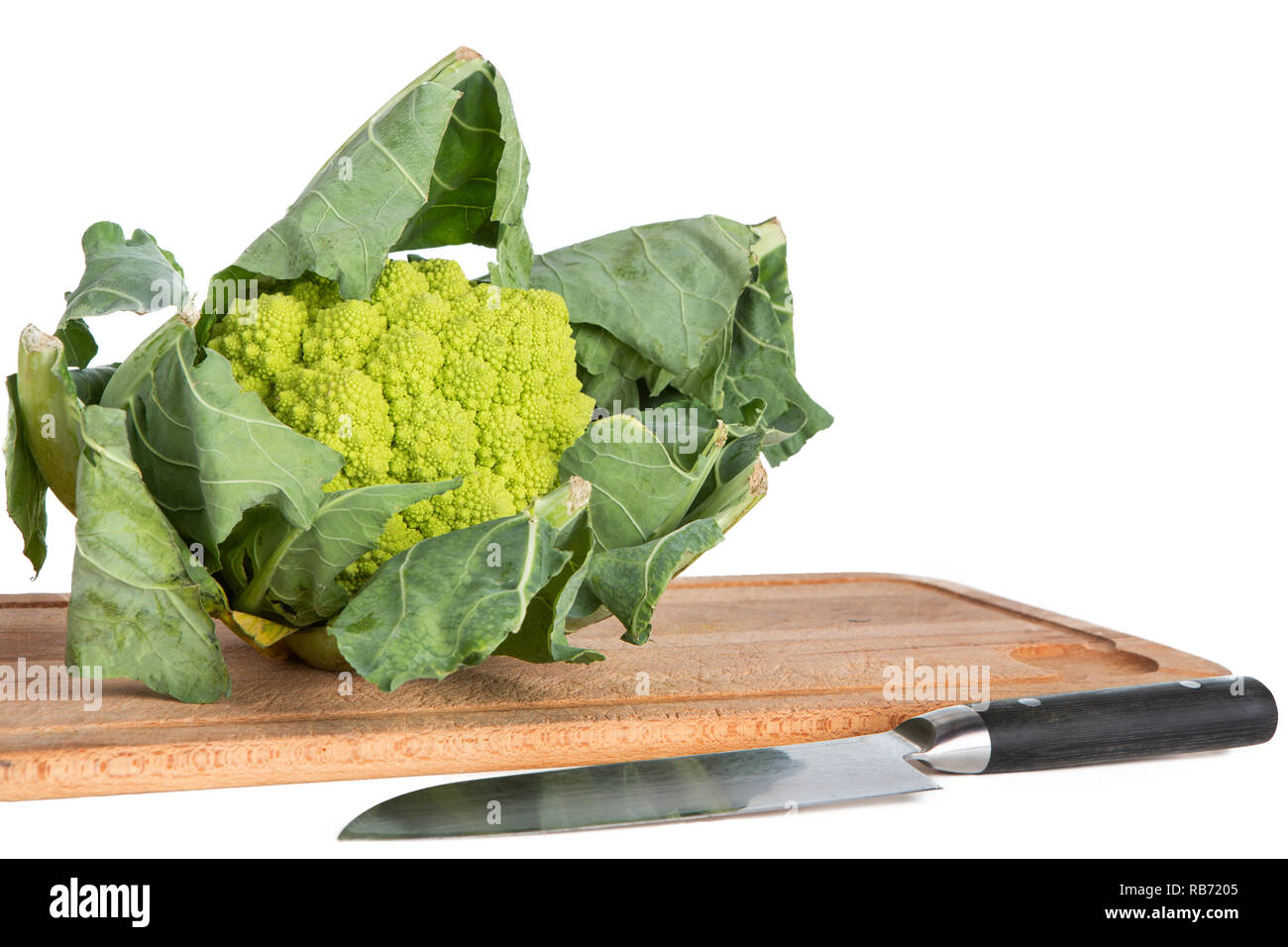 Romanesco cabbage with leaves on a cutting board and knife on a white ...