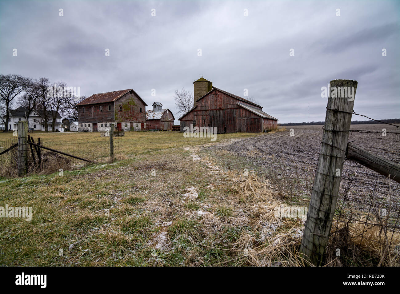 Fence post and barbed wire at the entrance to a rural midwest farm on a ...
