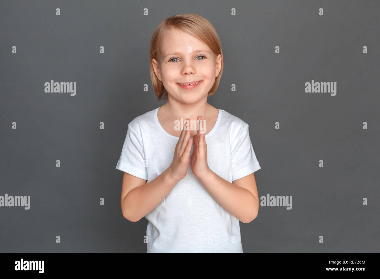Little girl standing isolated on grey wall clapping looking camera ...