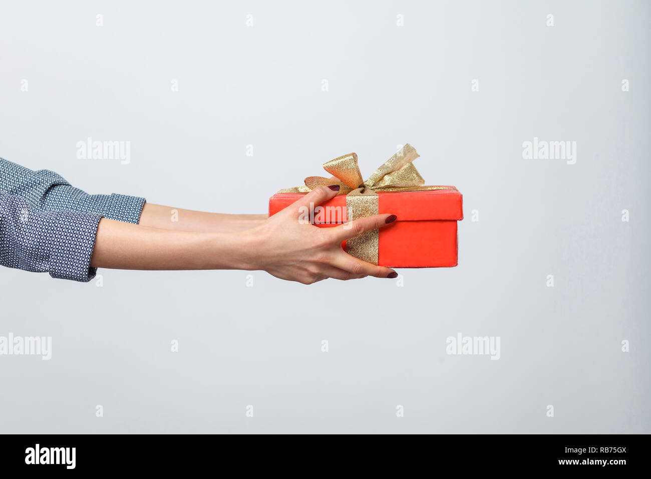 Beautiful female hands holding and giving you red box present with ...