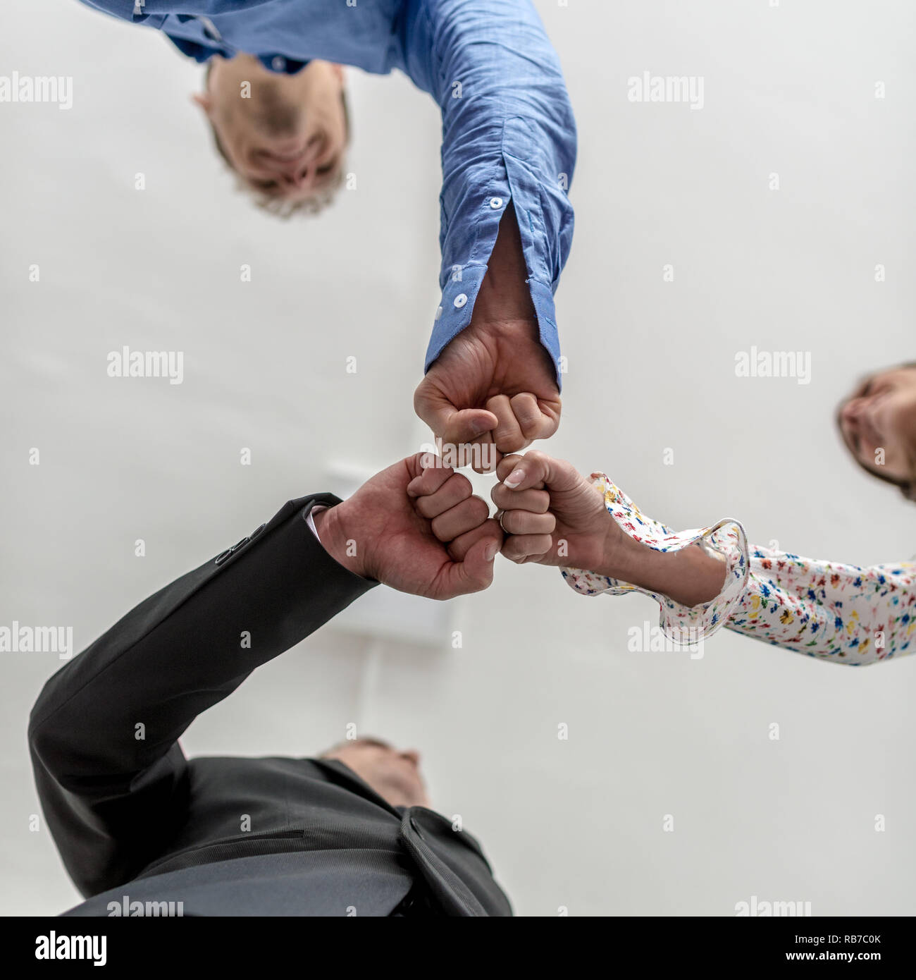 View from below of three business people bumping their fists together ...