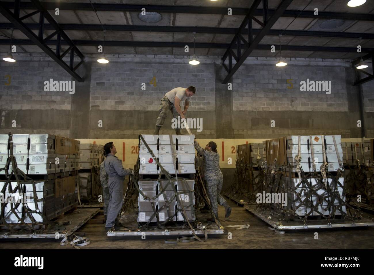 U.S. Air Force Airmen tie down and secure munitions to pallets during a ...