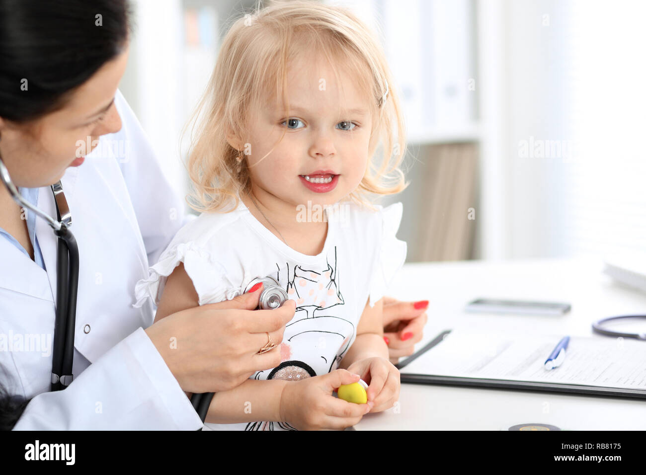 Doctor and patient baby in hospital. Little girl is being examined by ...