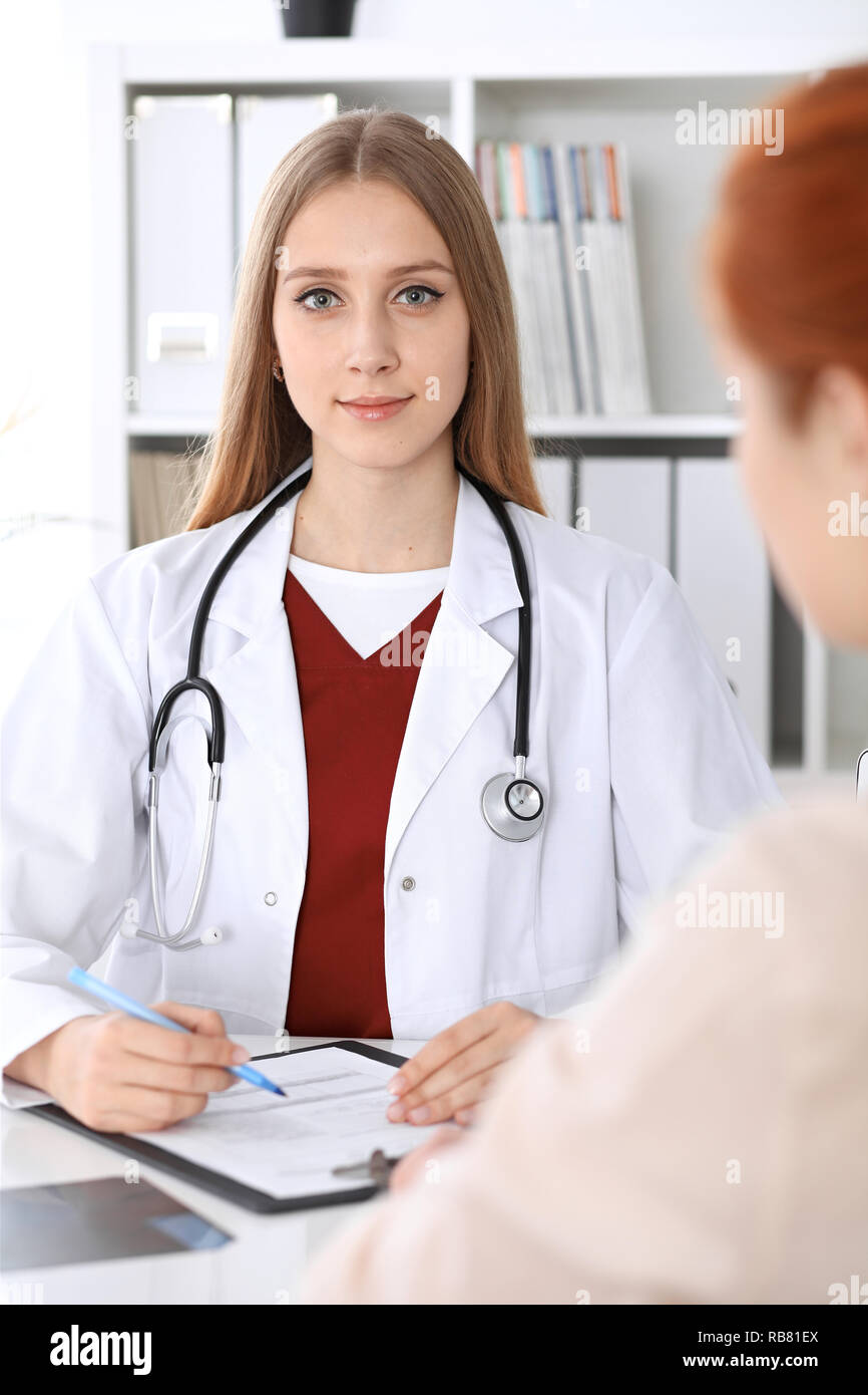 Close-up of a female doctor filling up an application form while ...