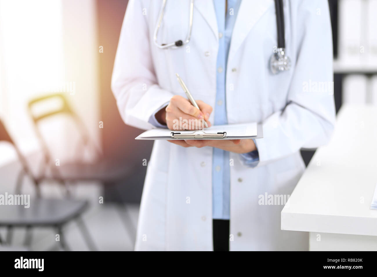 Doctor woman filling up medical form while standing near reception desk ...