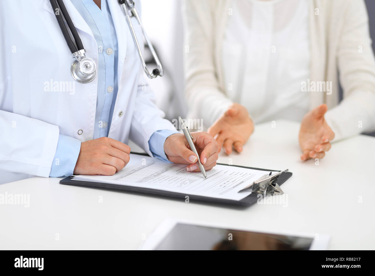 Unknown doctor and female patient discussing something while standing ...